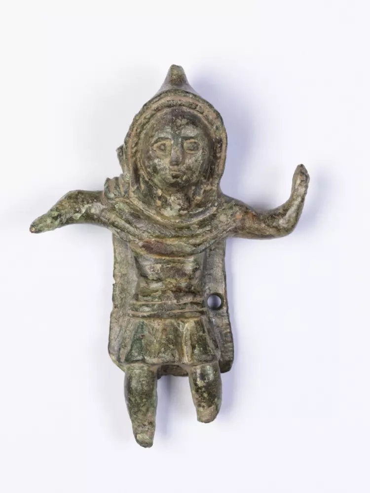 Against a white background, a small figurine with one arm raised and the other extended, wearing a hooded cloak