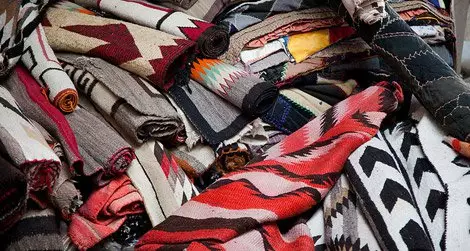 En potentiel køber skal omhyggeligt inspicere tæpperne på Navajo tæppeauktionen
