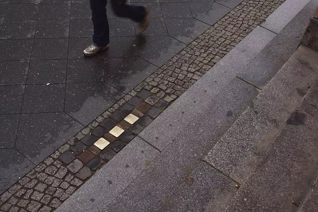 Stumbling stones along a street with legs of a person walking by