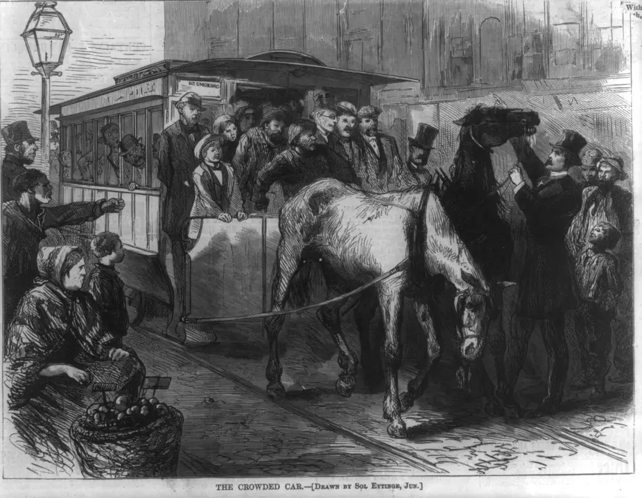 Мужчина в цилиндре трогает лошадь, тянущую трамвай, когда усталая лошадь опускает голову