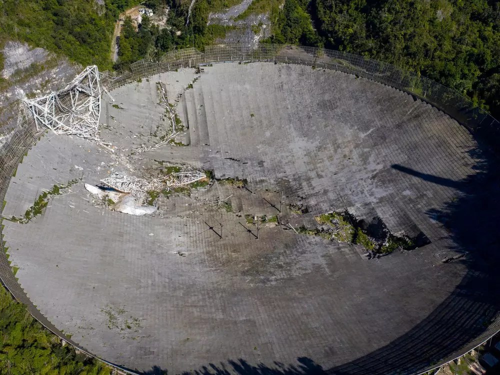 この空中写真は、2020年12月1日にプエルトリコのアレシボで受信機を保持している主要ケーブルの1つが壊れた後の、アレシボ天文台での損傷を示しています。