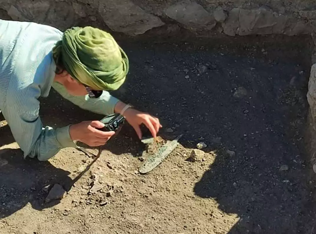 باستان شناس در حال بررسی سنگ ها در محل حفاری