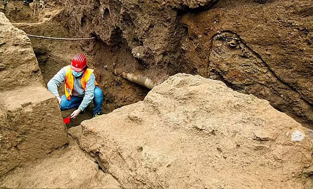 arkæolog arbejder inde i en rende af udgravet gravplads