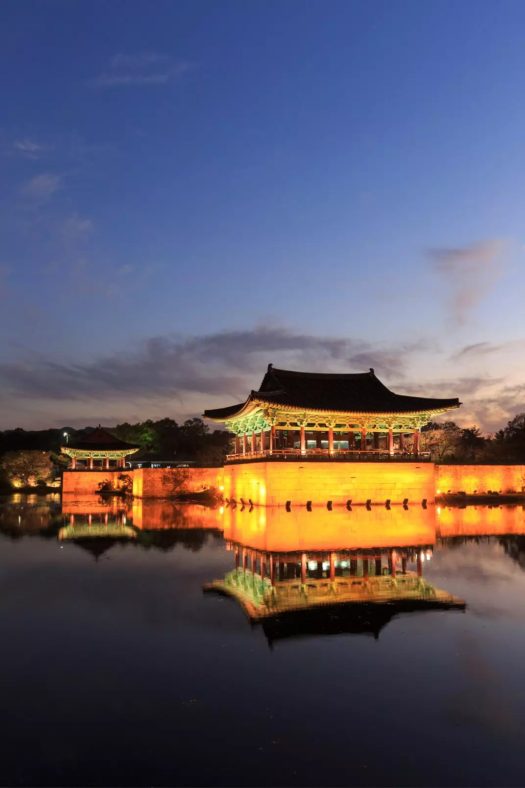 Корейски дворец, осветен през нощта над езерце