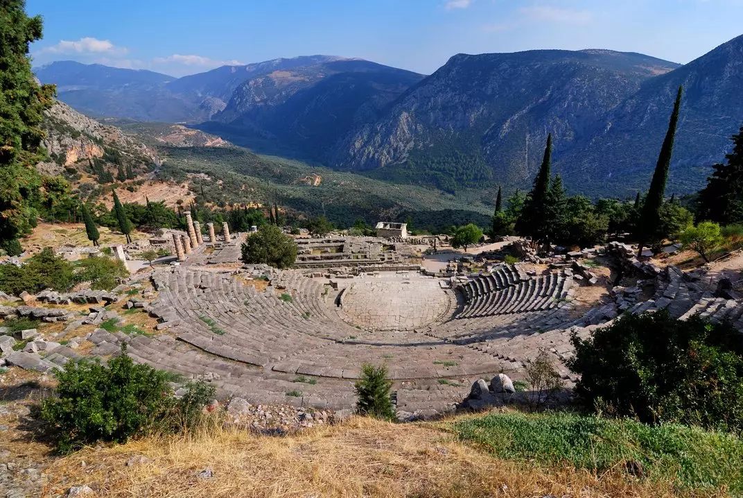 Kalna nogāzē iebūvētais akmens teātris ar Apollona templi un kalniem fonā