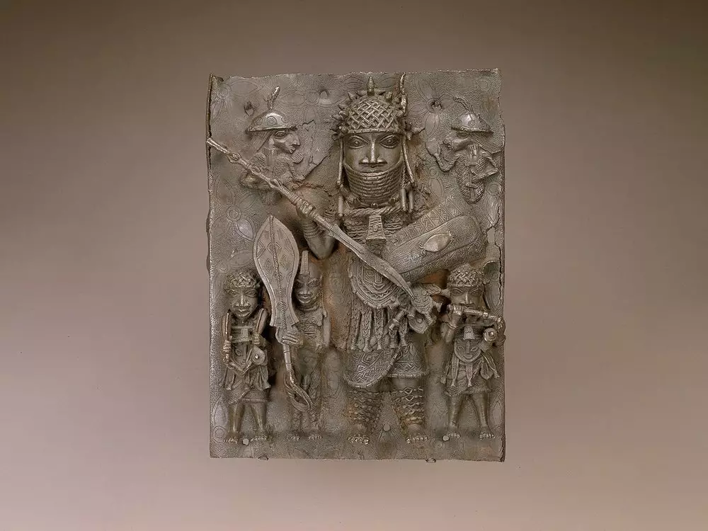 Een weergave van een bronzen plaquette met een afbeelding van een oba, of koning, met een speer en een zwaard boven kleinere figuren onder hem