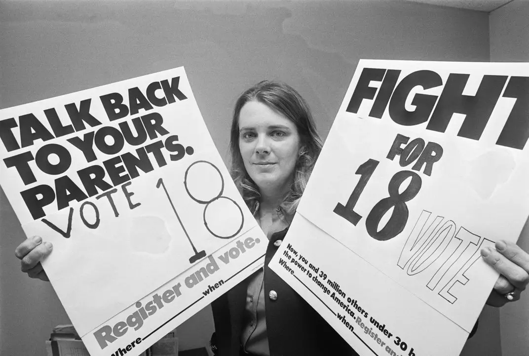 Femeie ținând pancarte pe care scrie „Vorbește înapoi cu părinții tăi”. Votează 18 și Luptă pentru 18