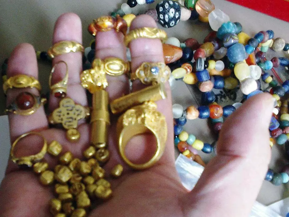 gioielli d'oro e perline tenuti in mano