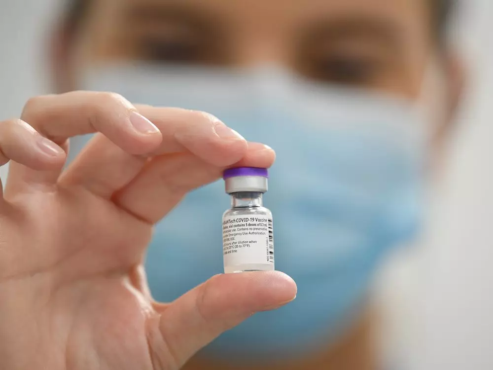 hawak ng isang doktor ang isang vial ng Pfizer covid vaccine patungo sa camera