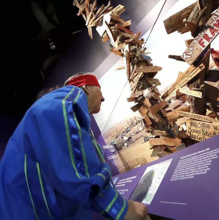 Plaku Onondaga duke parë një shtyllë miljeje në një ekspozitë muzeu