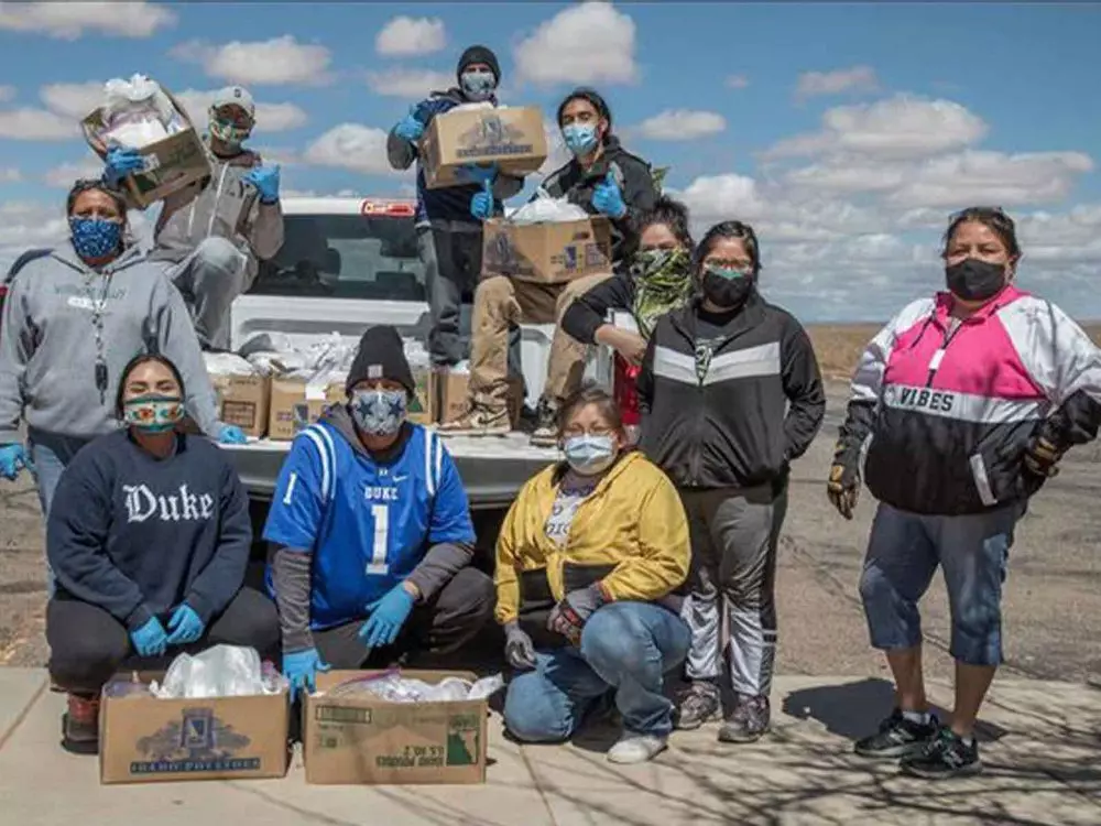 Navajo 和 Hopi Families Covid-19 Relief Fund 的志願者向 Navajo Nation 和 Hopi Reservation 的偏遠社區和農莊分發食物和其他必需品。作為史密森尼學會的虛擬節目 24 Hours in a Time of Change 的一部分，Shandiin Herrera（Diné）——坐在左邊，身穿杜克大學運動衫——描述了去年春天草根對 COVID-19 大流行的反應是如何聚集在一起的，並分享了她在猶他州紀念碑谷擔任基金志願者協調員的經歷。 （卡尼·哈奇攝）