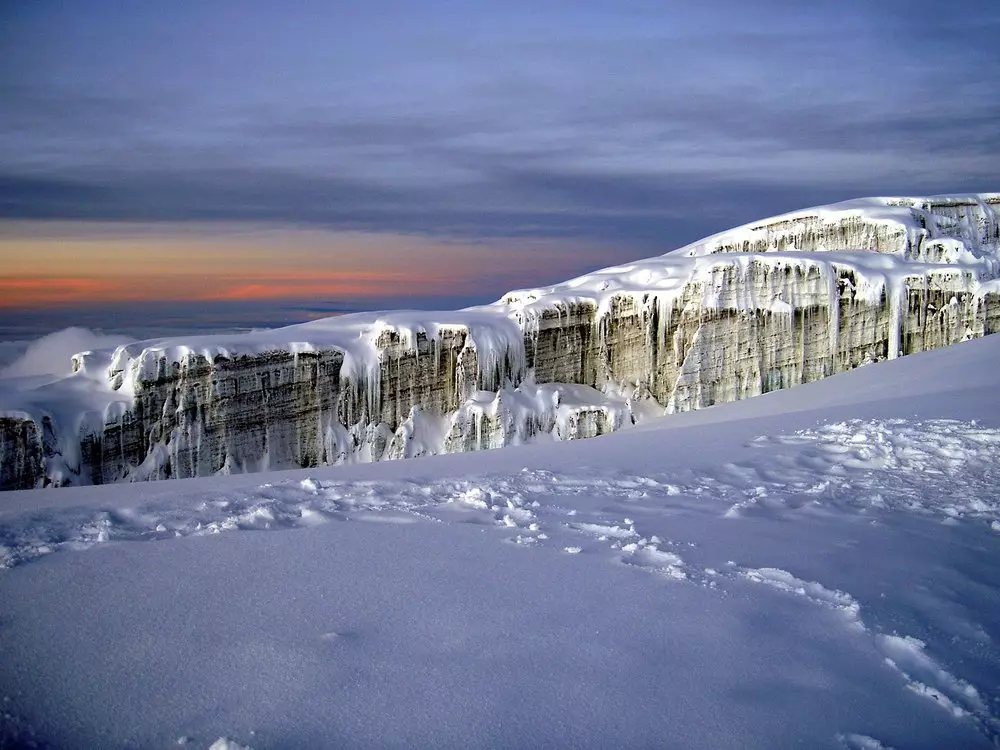 Tvár rozoklaného bieleho ľadovca na vrchole zasneženého úbočia hory