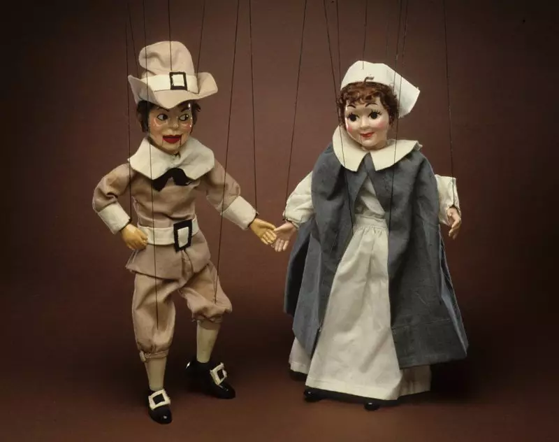 Zwei Marionetten, ein Mann und eine Frau, gekleidet in die mit Pilgern verbundene Kleidung, wie z. B. einen Männerhut mit einer auffälligen Schnalle.
