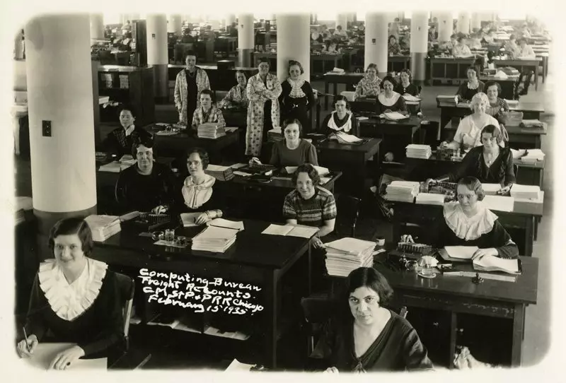 Decenas de mulleres sentadas detrás de filas de escritorios nun gran espazo de oficina
