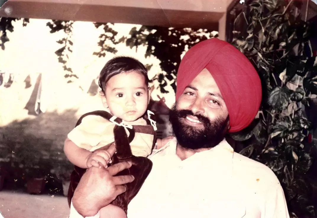 En ögonblicksbild av en man i en turban som håller ett litet barn i overall.