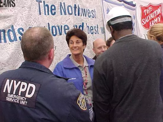 ผู้หญิงผมสั้นสีน้ำตาลยิ้มท่ามกลางตำรวจในเครื่องแบบ