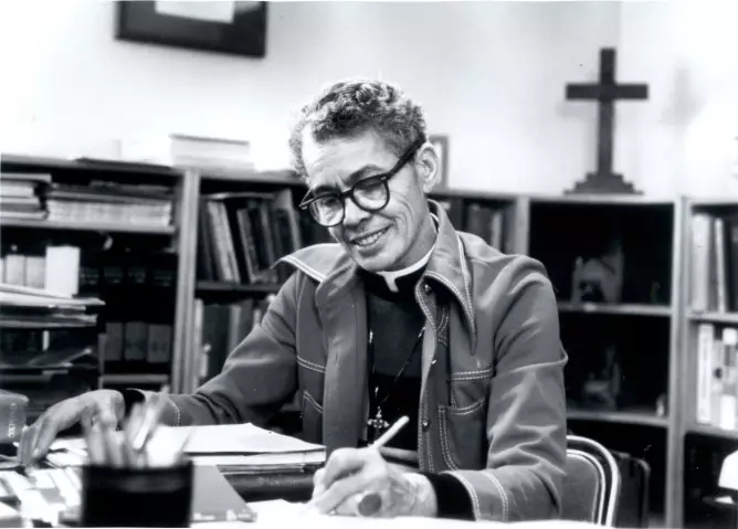 Pauli Murray sedí u stolu s křížem v pozadí