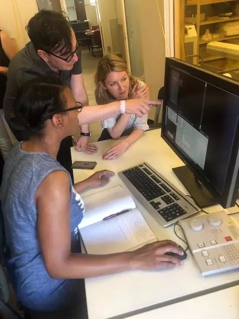 Sekelompok orang yang duduk di meja bekerja pada komputer di Museum Nasional Sejarah Alam Smithsonian.