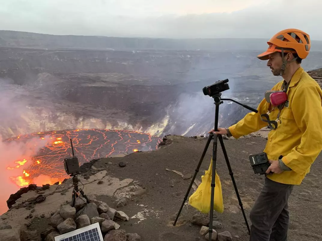 تصویری از یک زمین شناس در حال گرفتن عکس و فیلم از فورانی که در دهانه حلمائومائو در قله کیلاویا شروع شده است.
