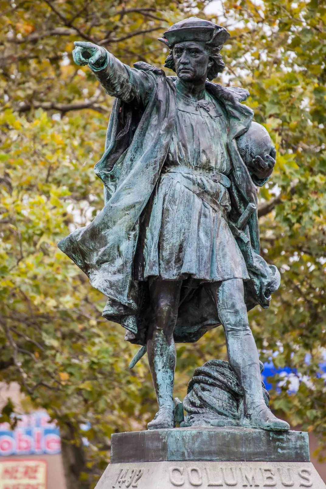 Srebrzystoniebieski posąg Kolumba trzymającego kulę ziemską i wskazującego palcem w autorytatywnej postawie