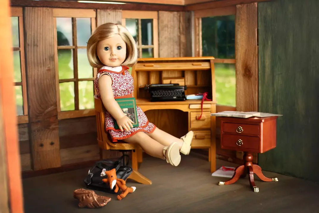 Kittredge-dukke sidder ved sit skrivebord på et midlertidigt loft