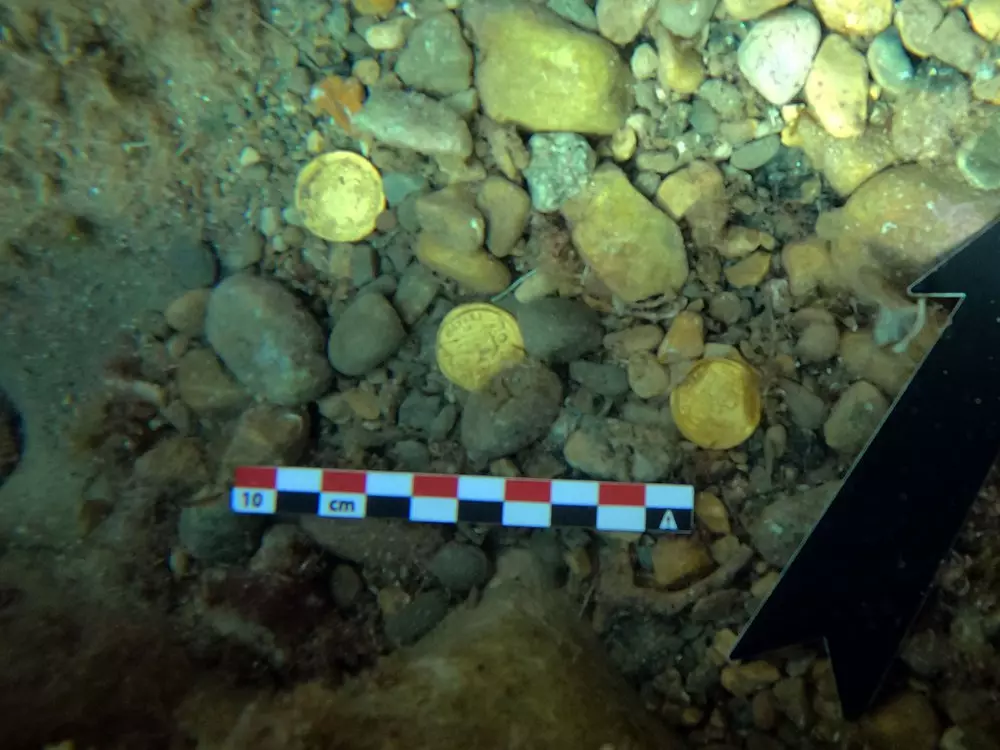 מטבעות מונחים בין אבנים קטנות מתחת למים
