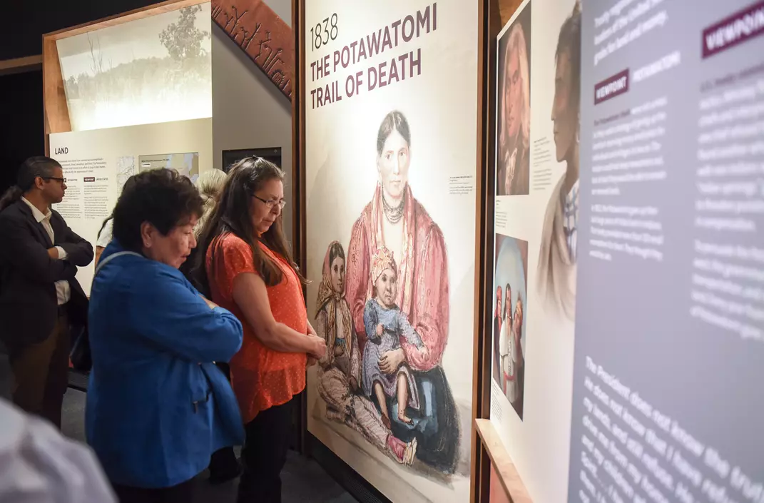 Seorang pemuda dan dua wanita membaca teks pameran berjudul 1838 Jejak Air Mata Potawatomi. Panel diilustrasikan dengan reproduksi gambar dan lukisan para pemimpin Potawatomi abad ke-19.