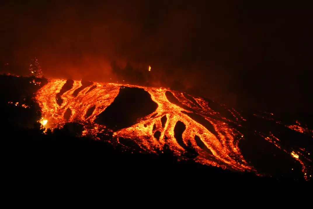 'n Beeld van 'n vulkaan op die Spaanse eiland La Palma wat swerwers van gesmelte helderrooi lawa uitspoeg