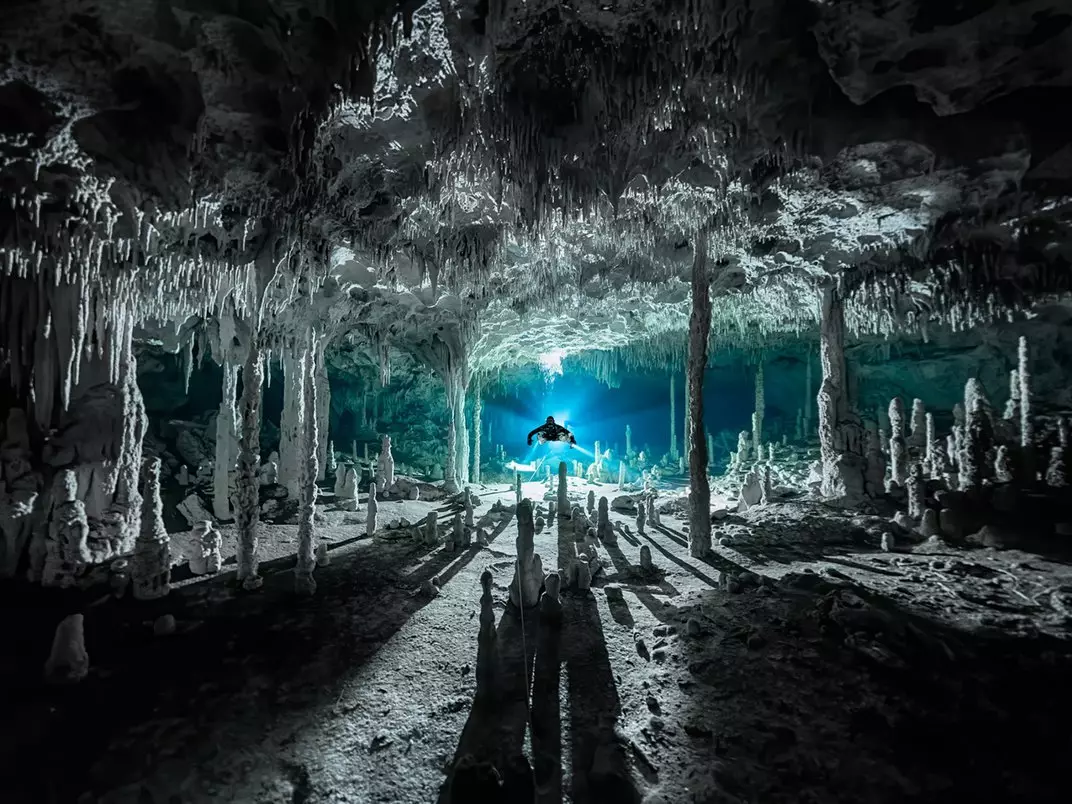 Gua bawah laut yang gelap dengan stalagmit dan penyelam dengan cahaya