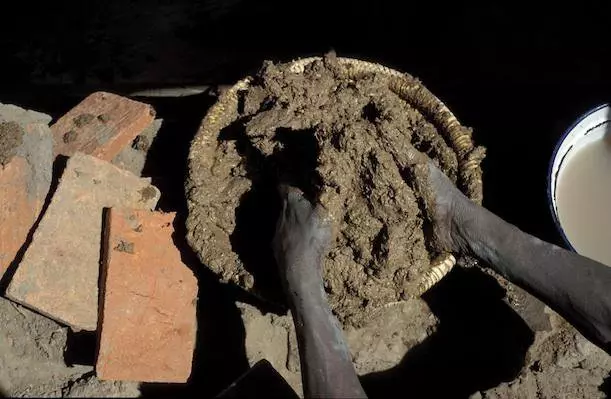 Ein Maurer bereitet Lehmmörtel vor.
