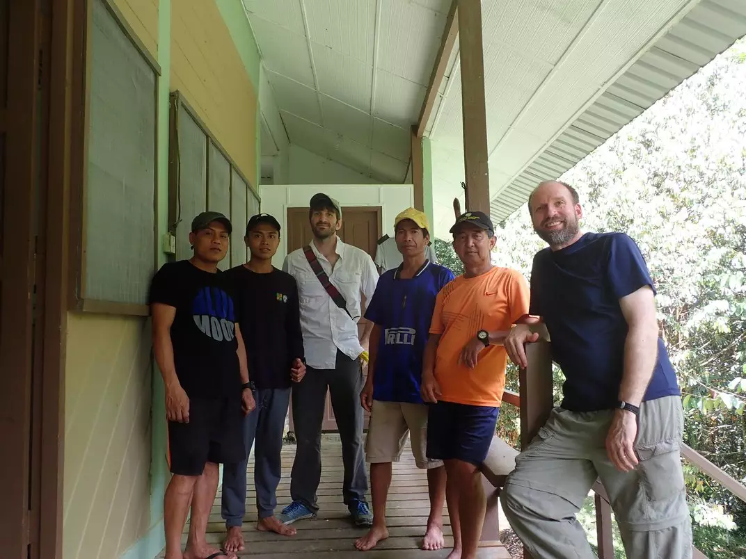 Jacob Saucier kaj Christopher Milensky pozas kun lokaj gvidistoj sur verando en Borneo.