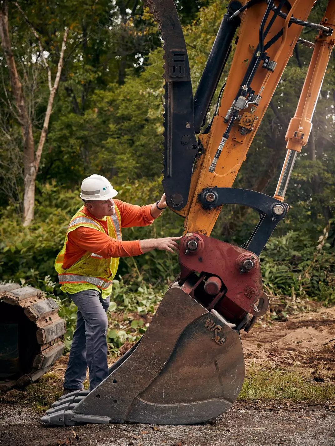 un muncitor în construcții inspectează un excavator pentru a detecta mușca-lanterne