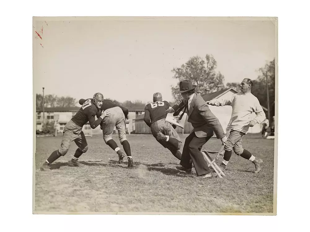 Fotografia de John Steuart Curry desenhando um treino de futebol na Universidade de Wisconsin-Madison, 1936 ou 1937 / fotógrafo não identificado. John Steuart Curry e documentos da família Curry, 1848-1999. Arquivos de Arte Americana, Smithsonian Institution.
