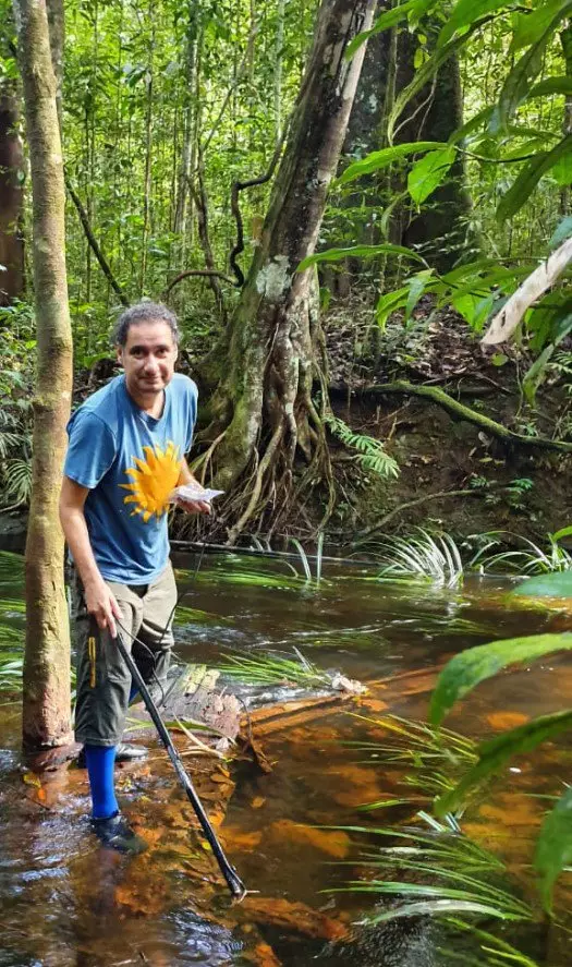 Smithsonian scientist David de Santana searching for electric eels in a river in the lush Amazon rainforest.