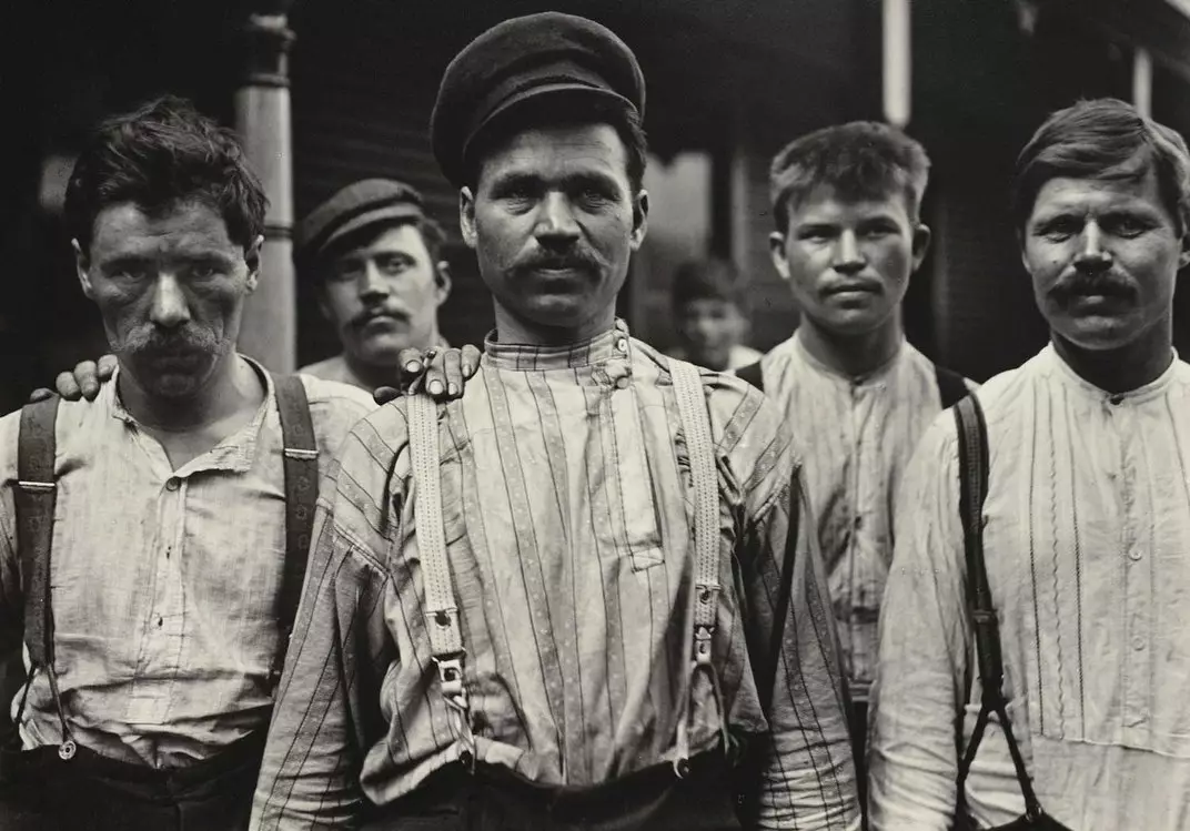 五個男人的黑白照片，都留著小鬍子和吊帶褲，有些人戴著帽子