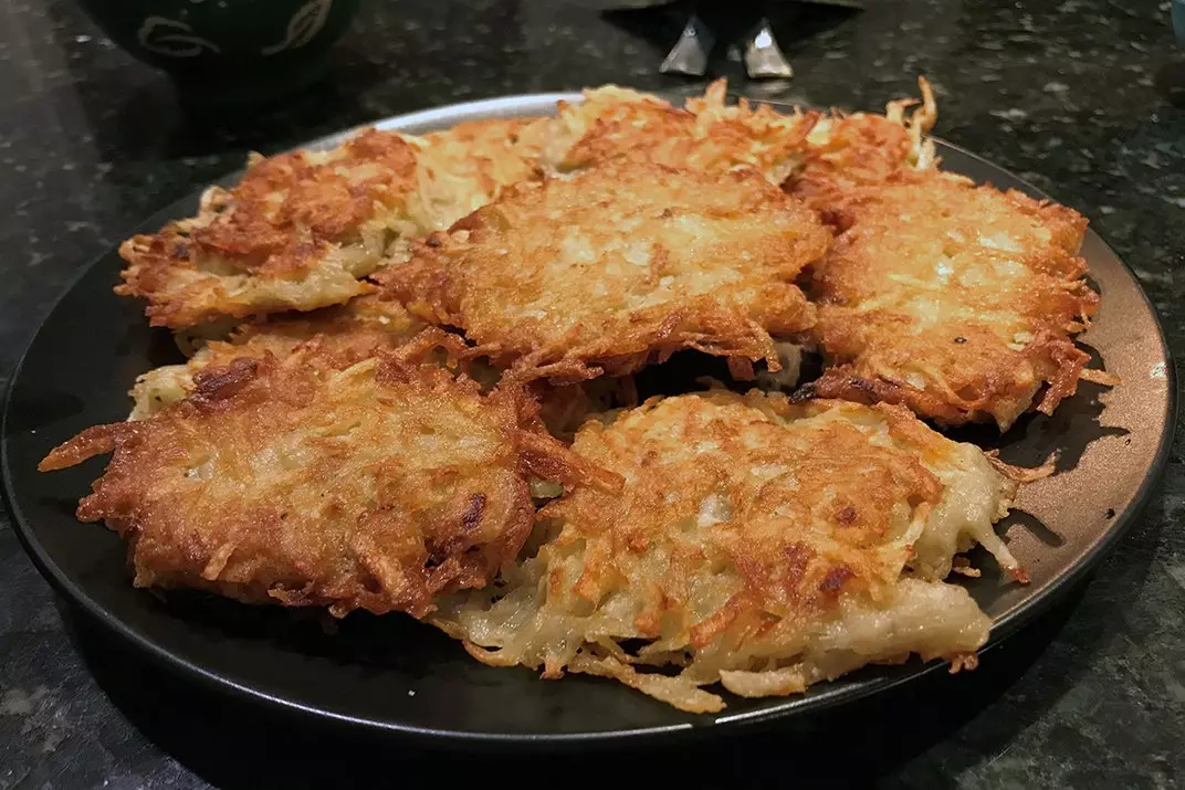 Goudbruine aardappelpannenkoekjes op een bord.