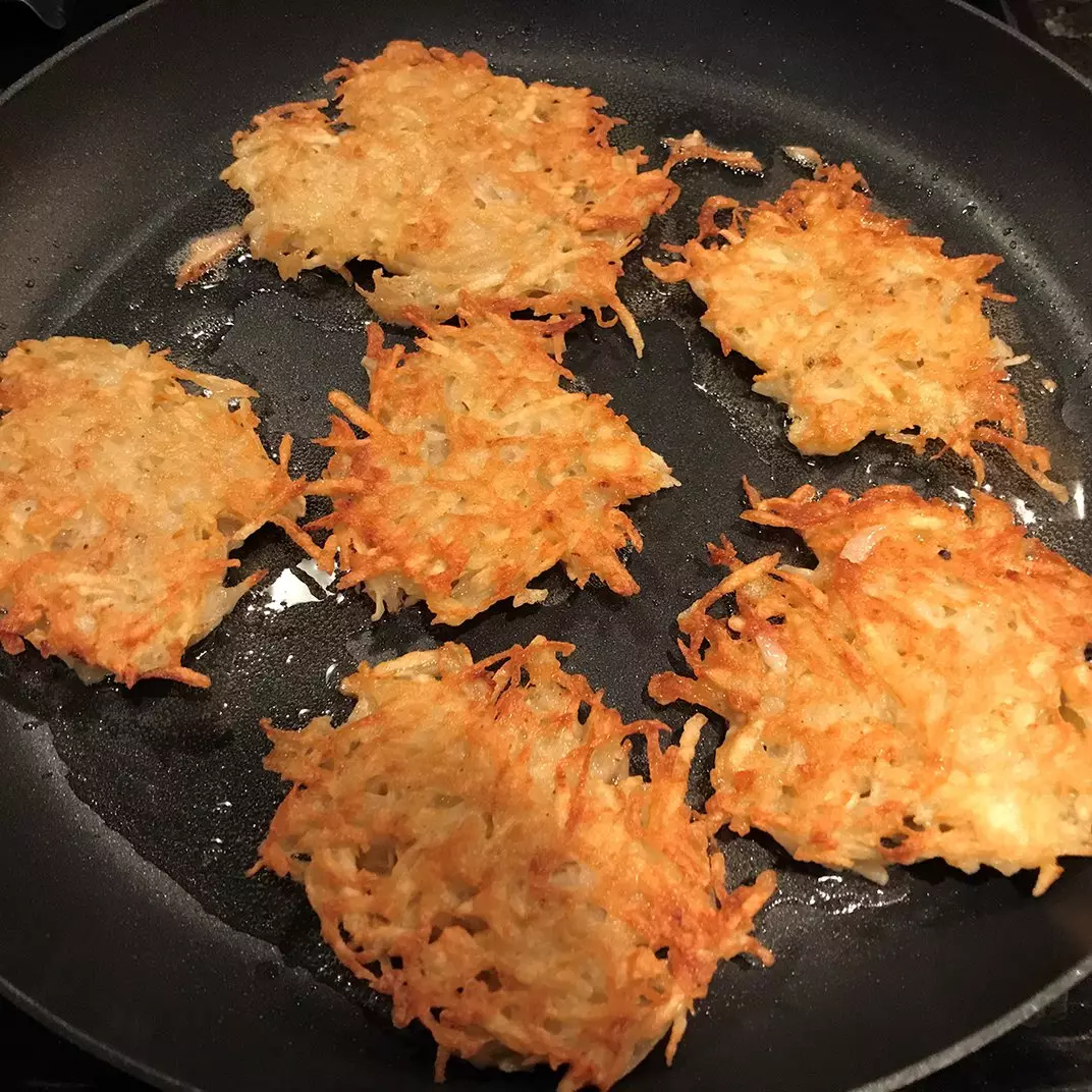 Goldbraune Kartoffelpfannkuchen, die in einer Pfanne braten.