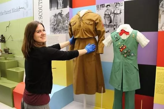 Curator care scoate două rochii din forme într-o expoziție