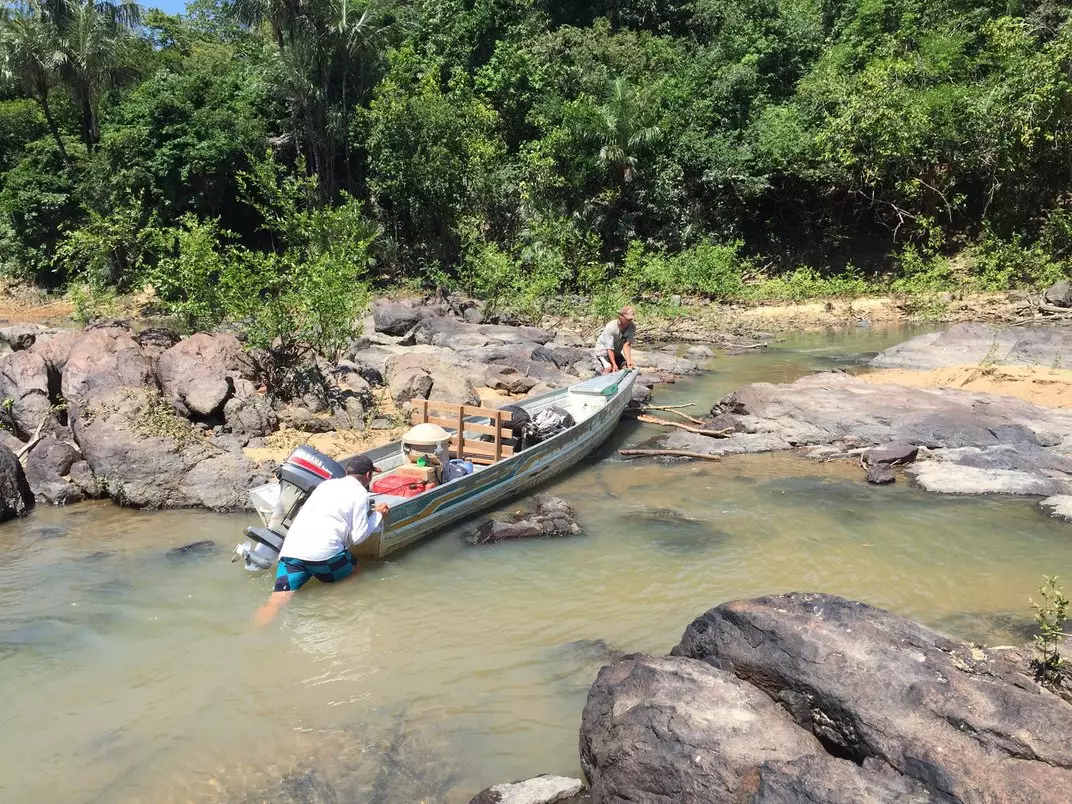 Två personer skjuter en liten båt i en flod.