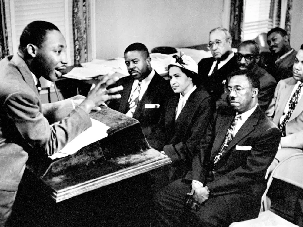 MLK Jr joqgħod fuq podju u jitkellem b'animazzjoni ma' grupp ta' seba' persuni oħra f'siġġijiet, inklużi Rosa Parks u Ralph Abernathy, li kollha joqogħdu quddiemu.