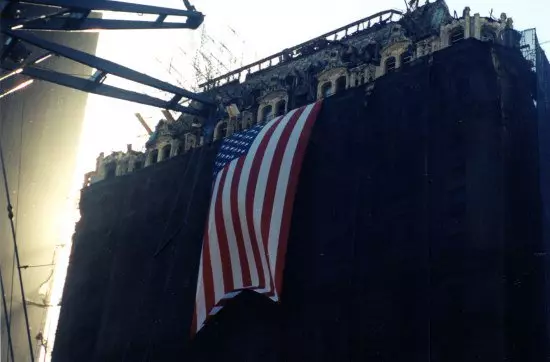Foto van 'n gebou wat steeds staan na aanvalle van 11 September 2001. 'n Groot Amerikaanse vlag hang aan 'n gebou. Die gebou is in swart gedrapeer.
