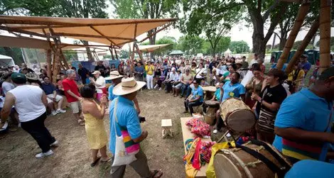 Apmeklētāji un mākslinieki mijiedarbojas zem gvaduas (bambusa) teltīm Kolumbijas programmas teritorijā.
