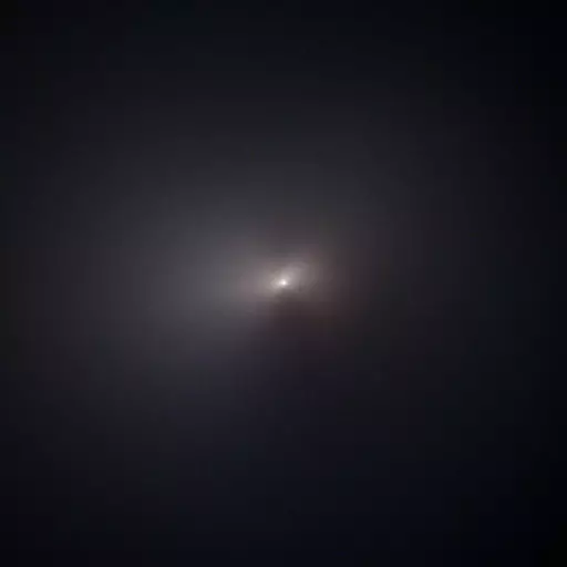 Hapësirë e zezë përreth, me një dritë relativisht të vogël të bardhë në qendër që lëshon një re të mjegullt drite. Drita është pak më e ndritshme në të dyja anët e kometës, gjë që tregon dy