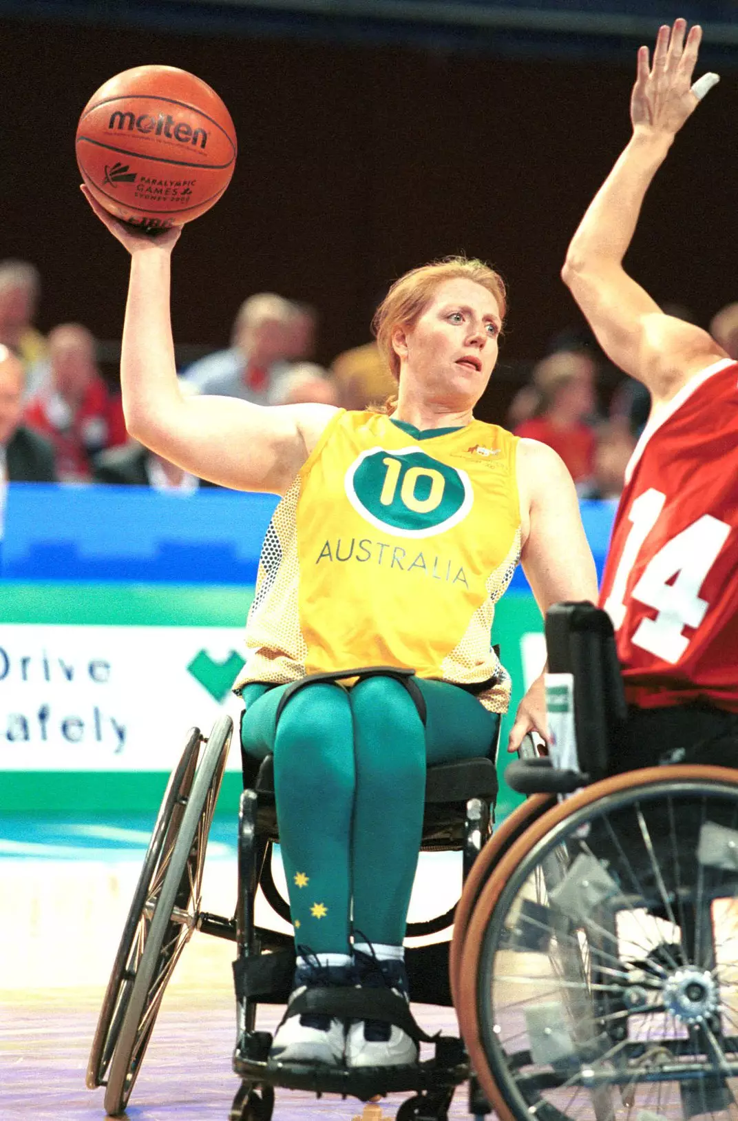 Женщина передает мяч во время игры в баскетбол на инвалидной коляске