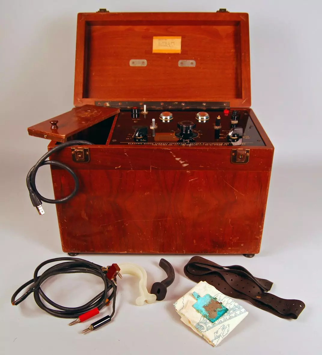 વાયર અને અન્ય એસેસરીઝ સાથે લાલ લાકડાનું ઇલેક્ટ્રોશૉક મશીન