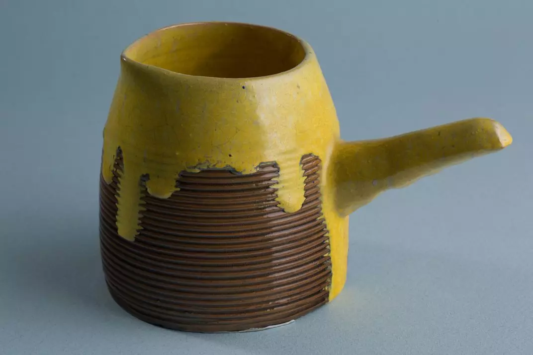 Un pot en céramique émaillé au sommet d'une glaçure jaune vif, dégoulinant sur ses côtés. Le fond du pot est émaillé dans un brun chaud et a une texture nervurée.