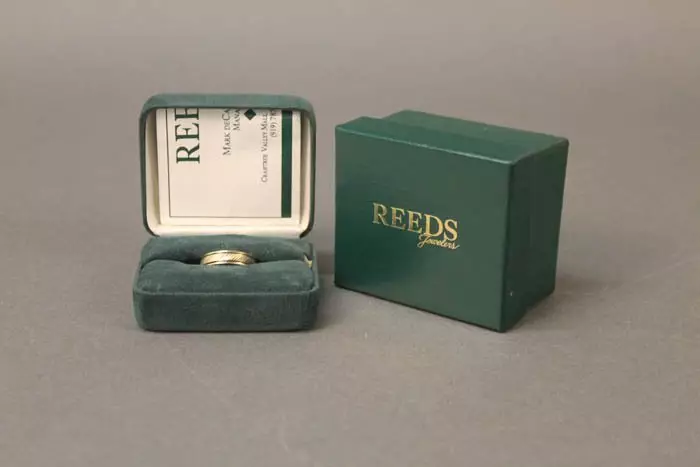 Золота обручка в темно-зеленій коробці для кілець