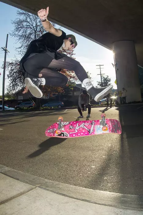 Dievča robí kick flip cez ružový skateboard