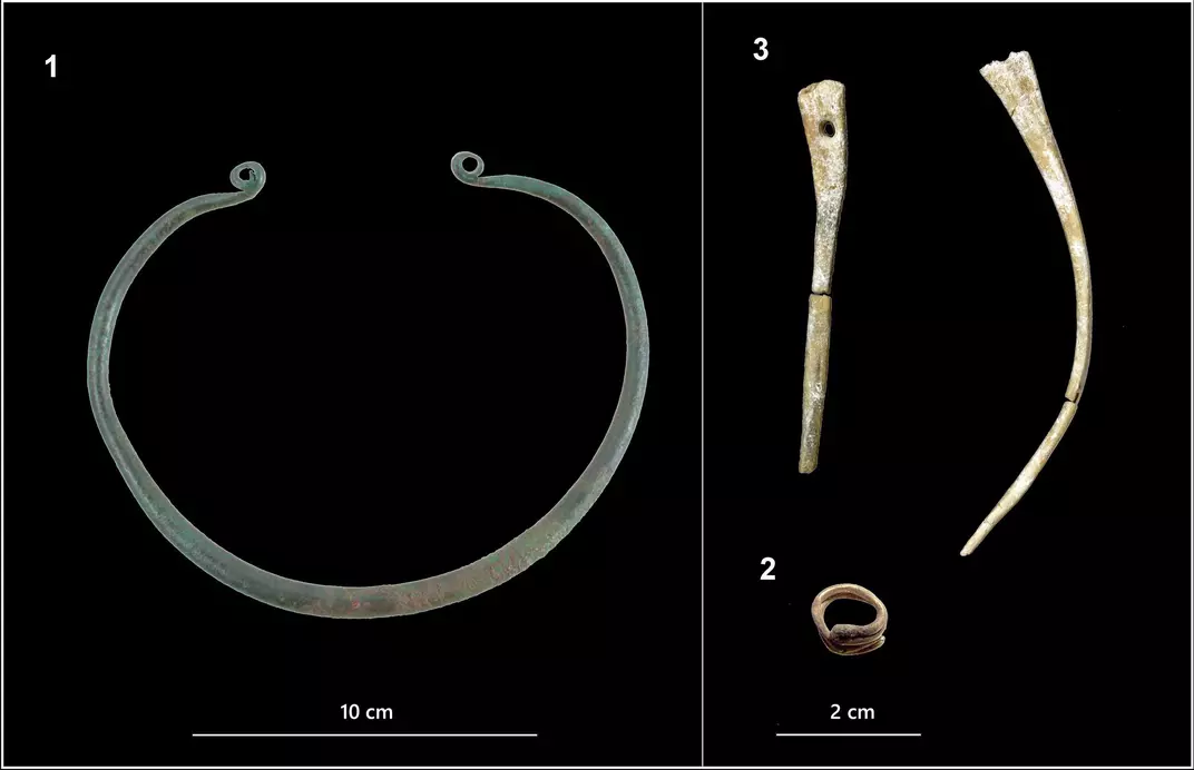 Các đồ dùng trong nhà mồ bao gồm một chiếc vòng đeo cổ bằng đồng (bên trái), hai chiếc kẹp tóc bằng xương và một chiếc vòng bằng vàng (bên phải).