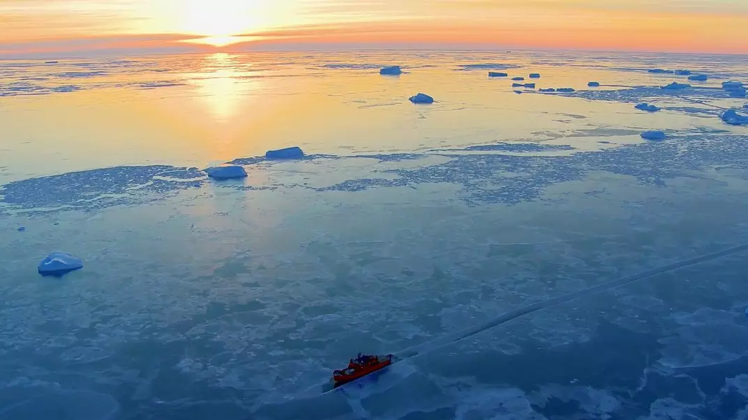 Laivas plaukia per ledo lakštus vandenyne saulei leidžiantis.